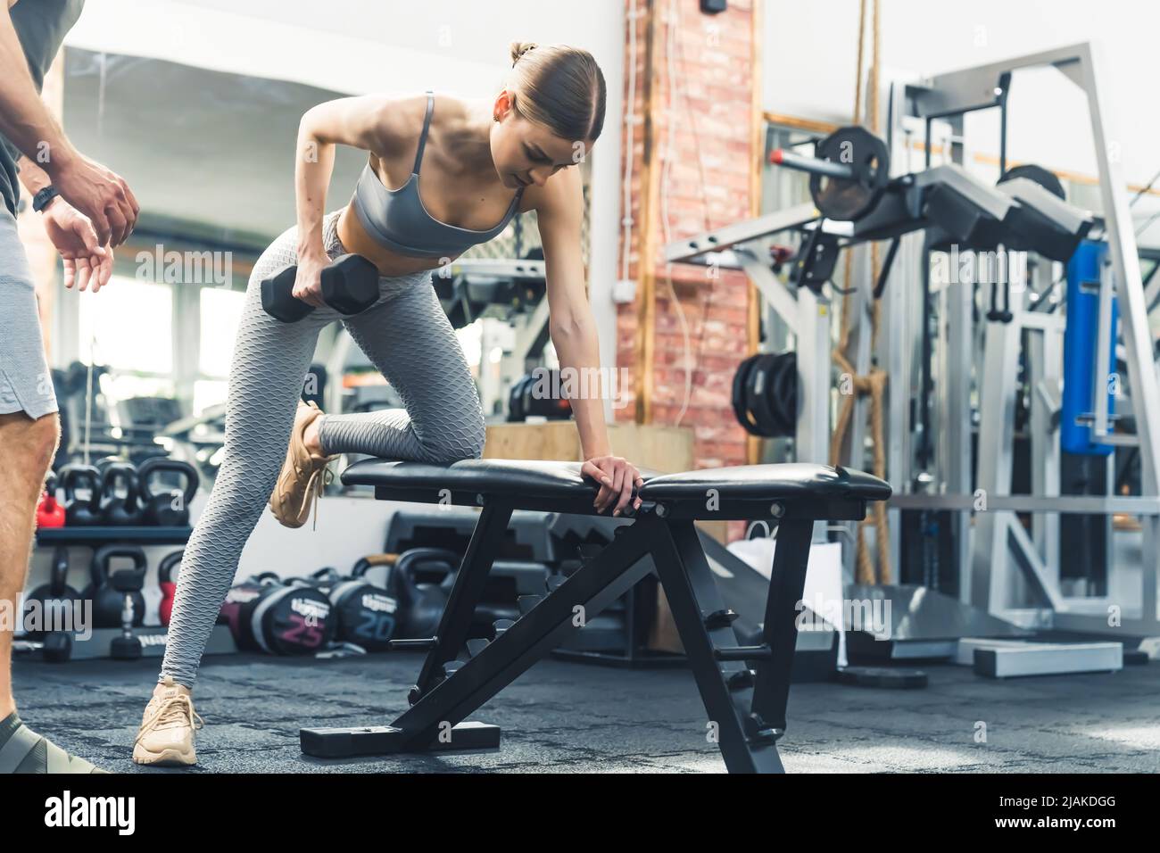 Attractive slenderly built dark-haired woman leaning towards a bench at ...