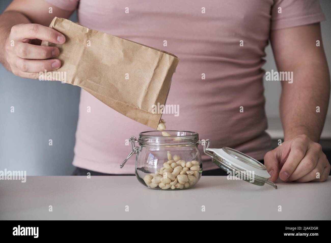 Unrecognizable latin man filling up a jar with peeled peanuts from a ...