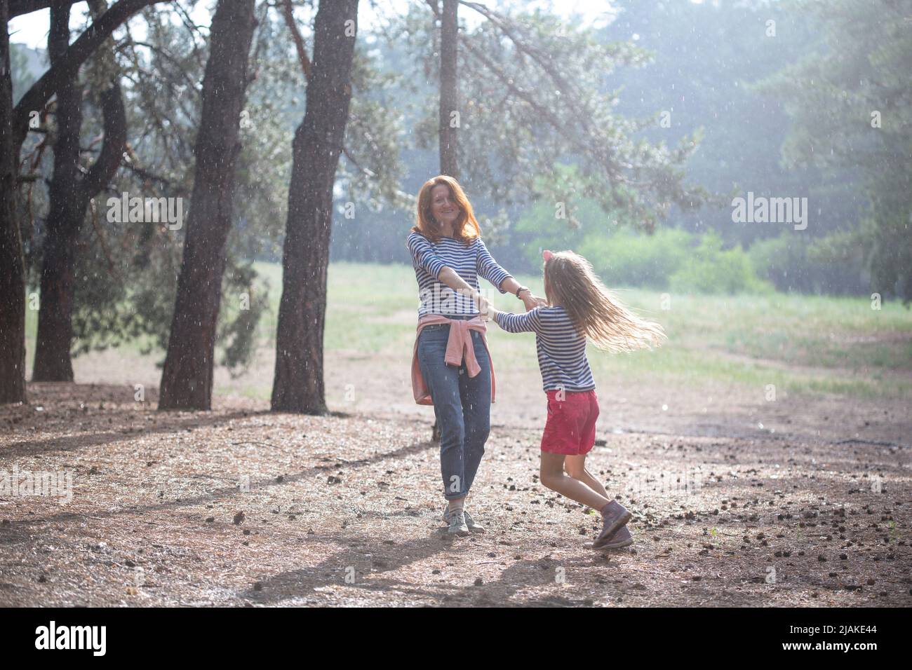 happy family - Mother and daughter on a walk under rain in the sunset ...