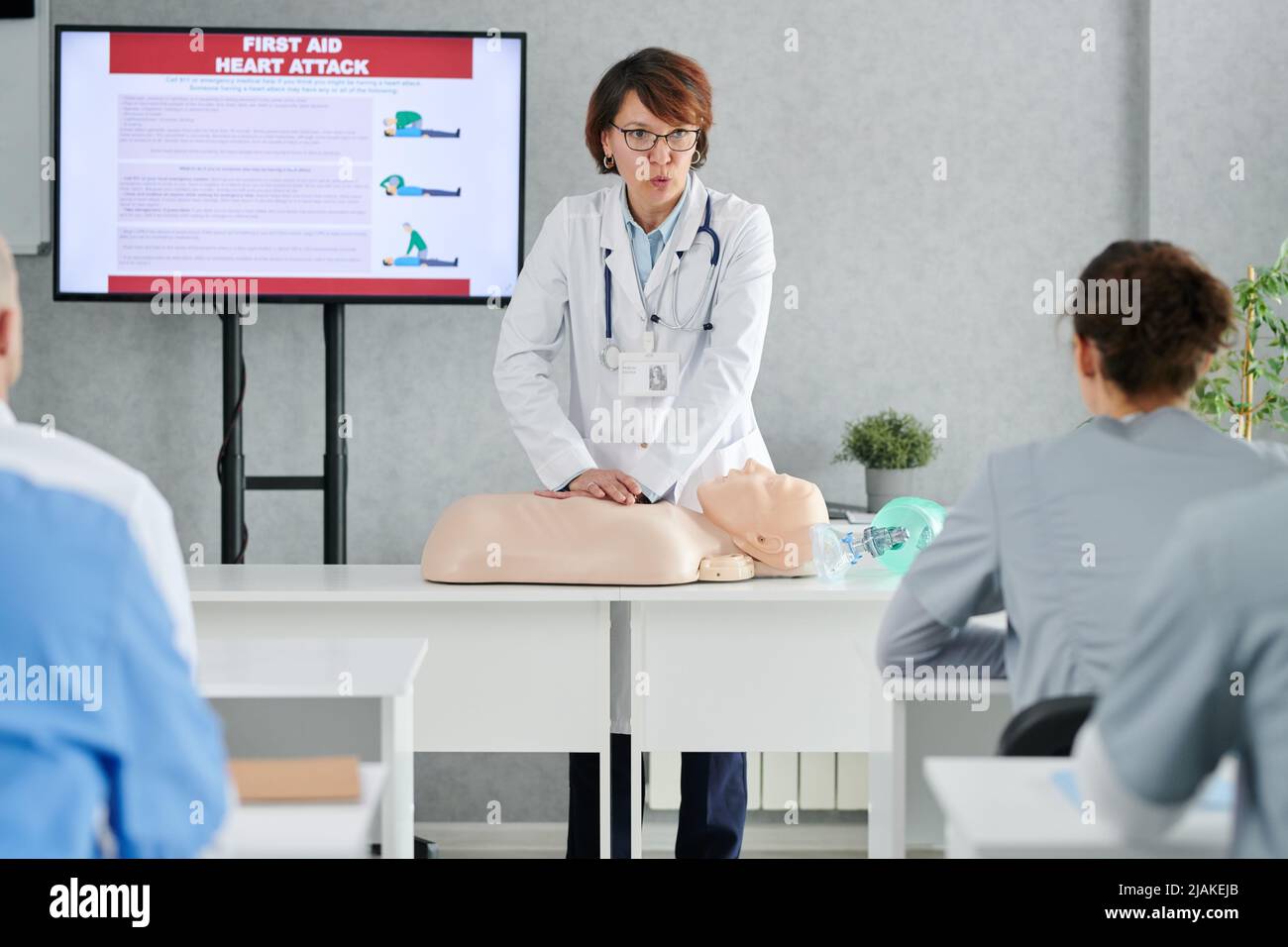 Medical specialist demonstrating on mannequin how to providing first aid to students at training ...