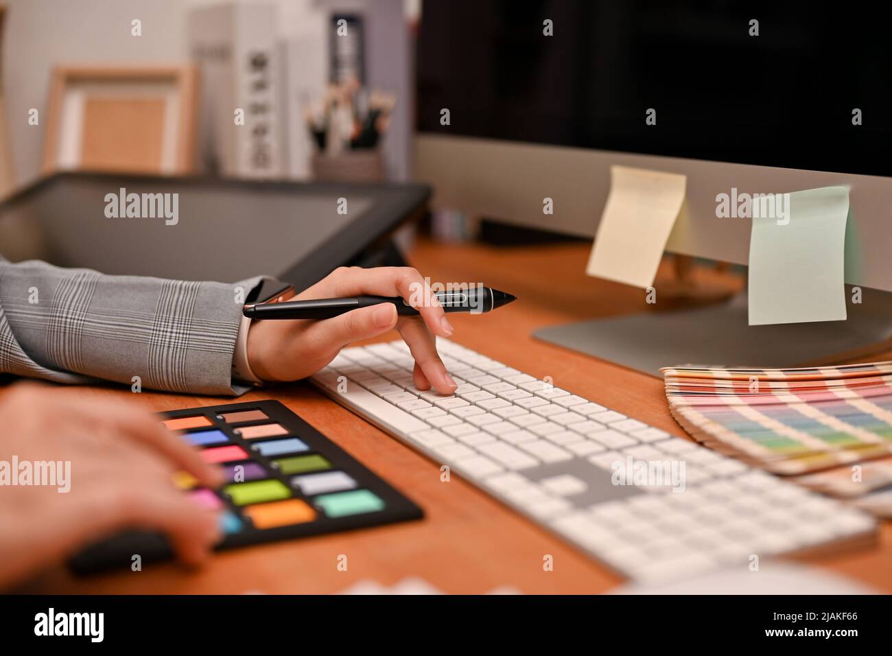 A successful female graphic designer holding a stylus one, typing on ...