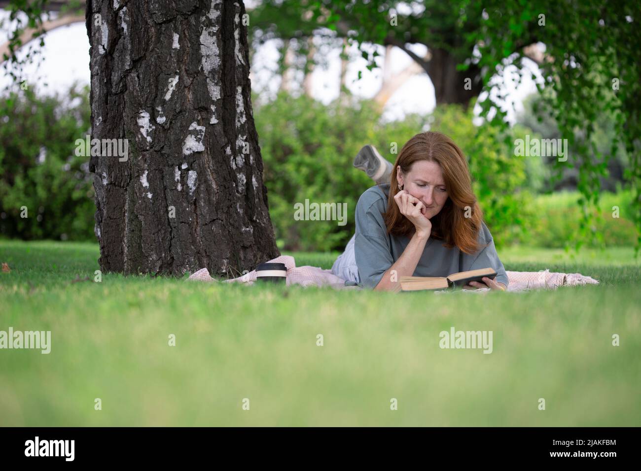 girl reading a book on the lawn Stock Photo - Alamy