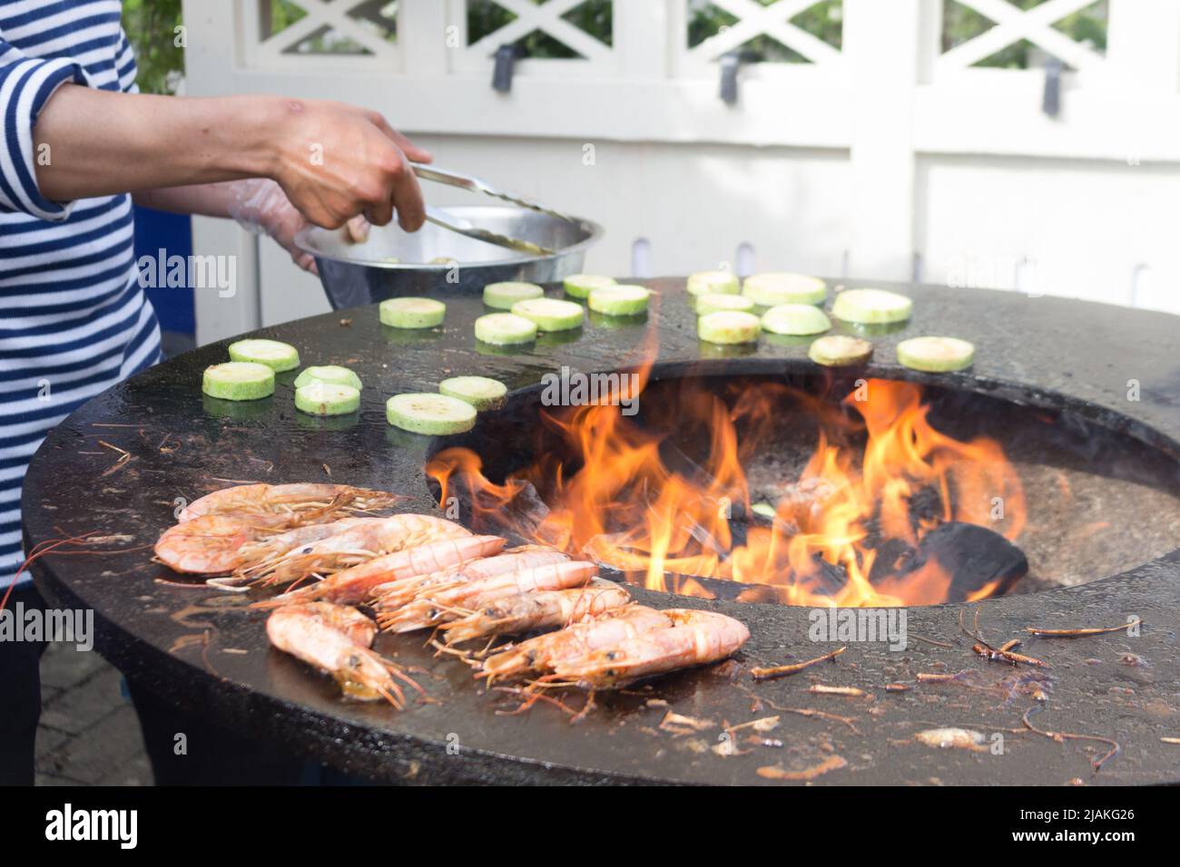 Cooking seafood on a brazier, open fire. Grilled shrimp and zucchini ...