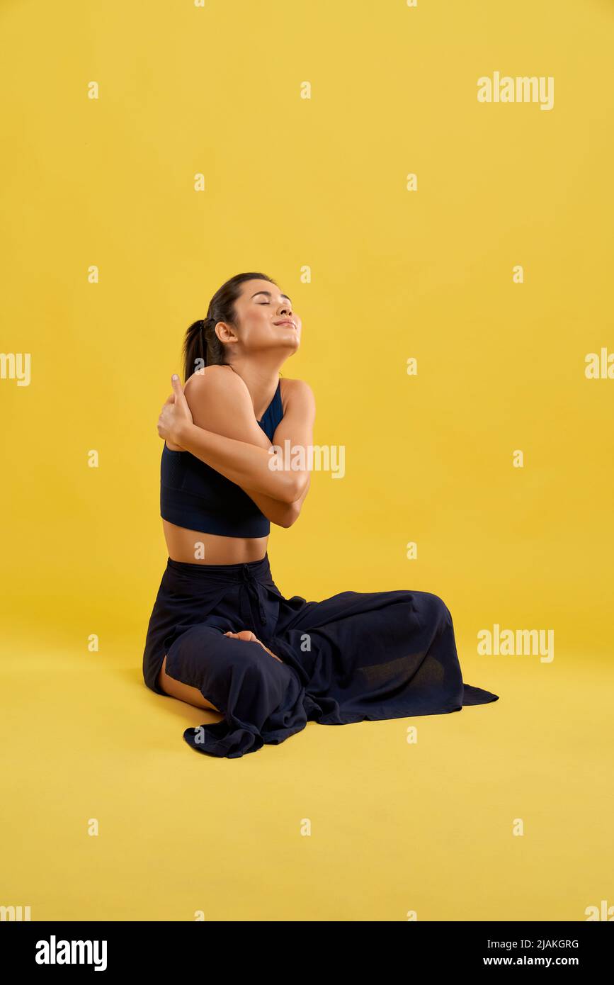 Young woman in spacious wear sitting in self hug pose, enjoying ...