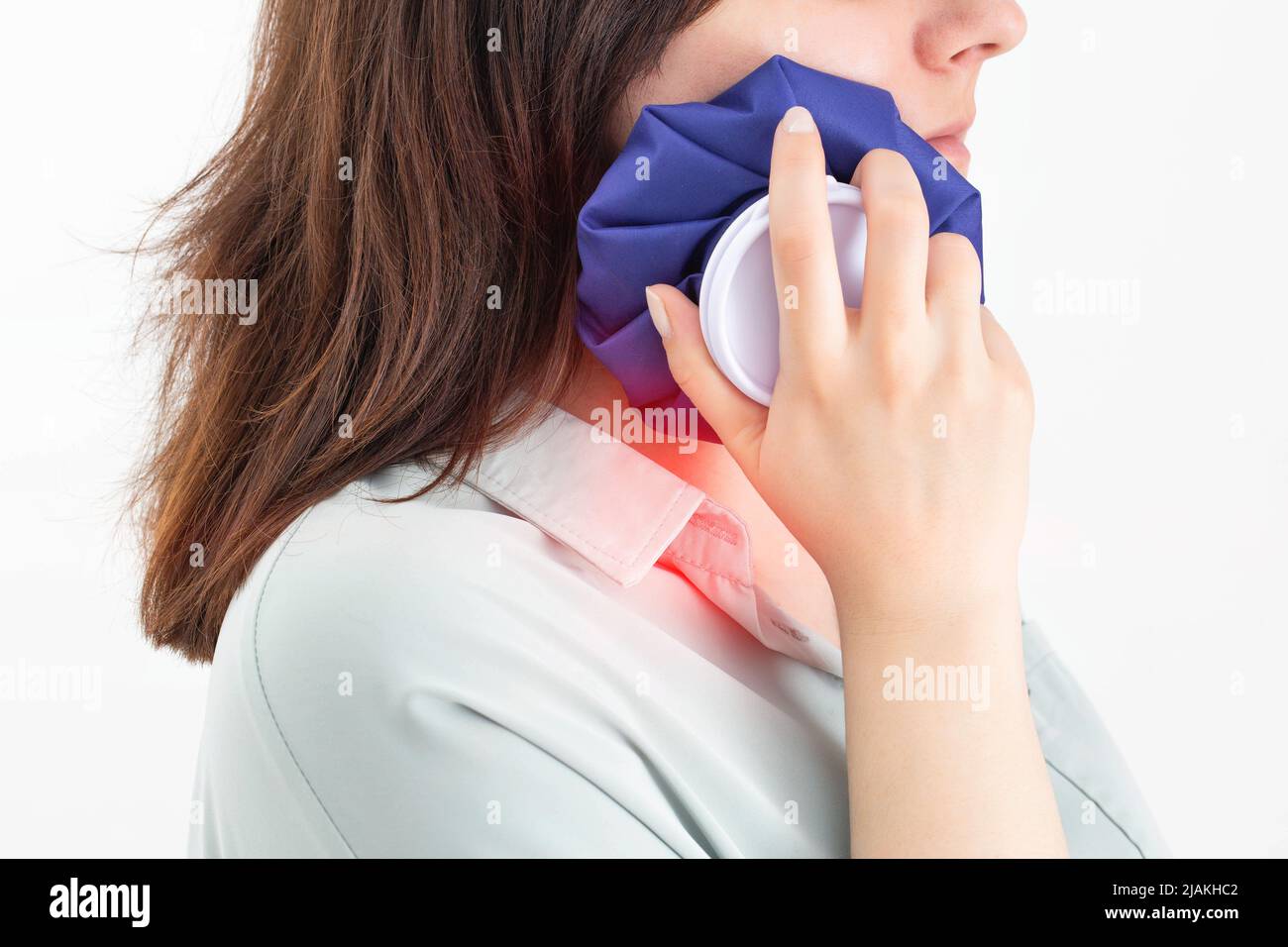 A girl attaches a medical bag with cold to the swelling on her cheek ...