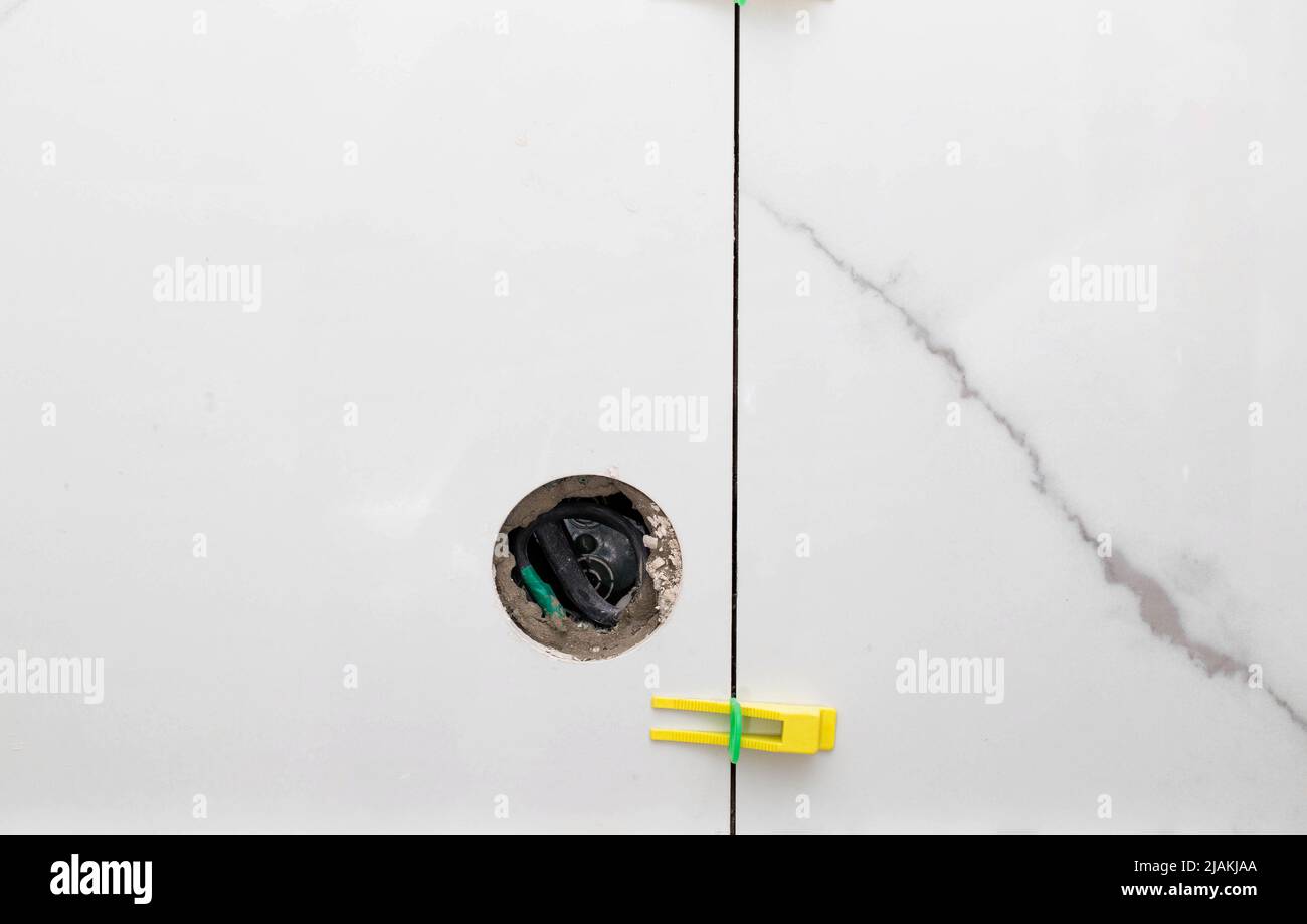 A hole in the wall with a tile for an outlet. Marble leveling system ...