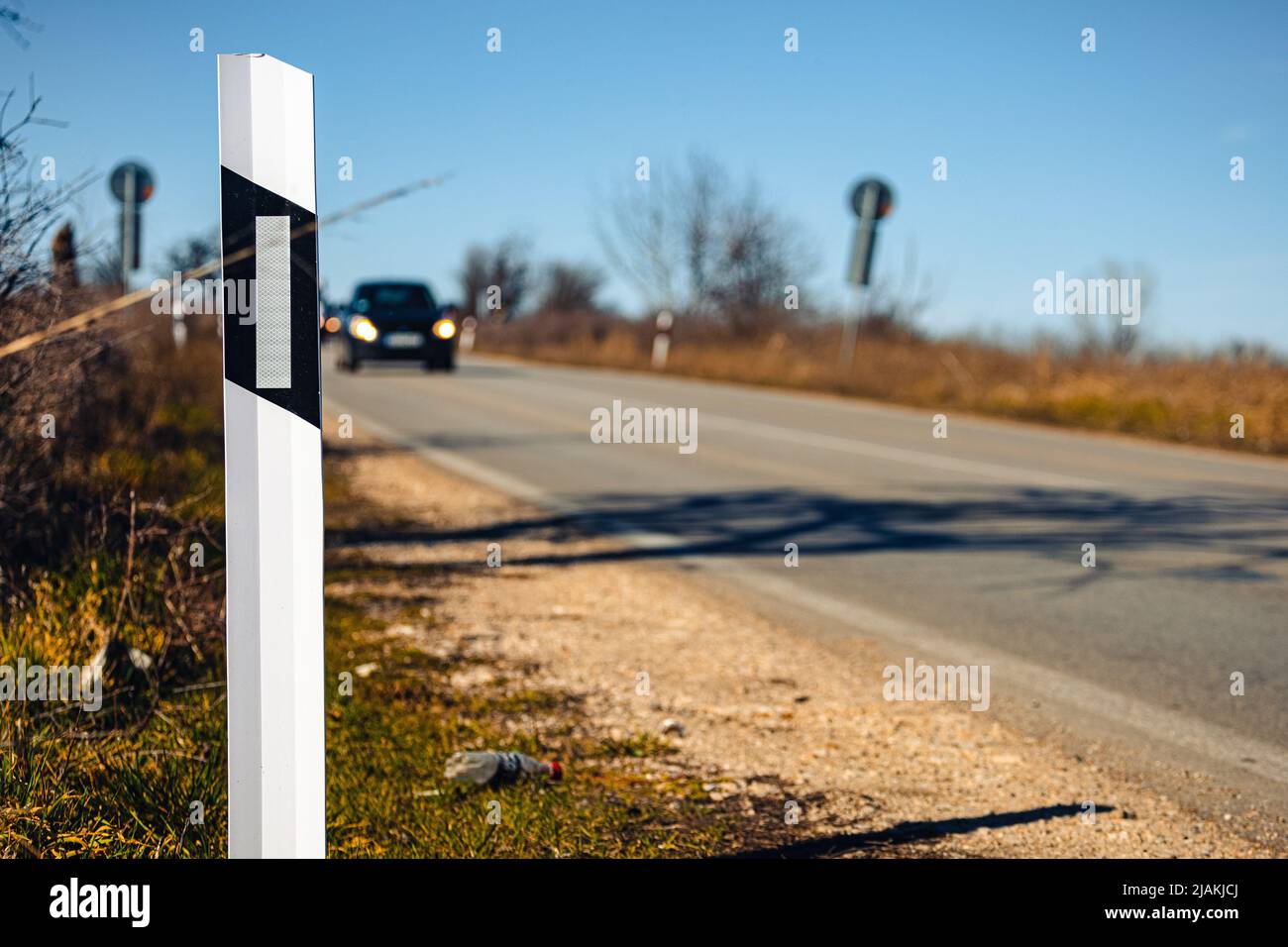 road sign to the road with an approaching car outside the city to the ...