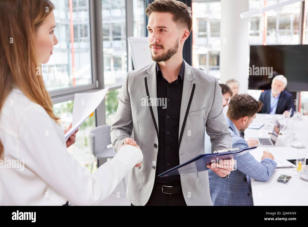 Young start-up founder and trainee shaking hands as a greeting or ...