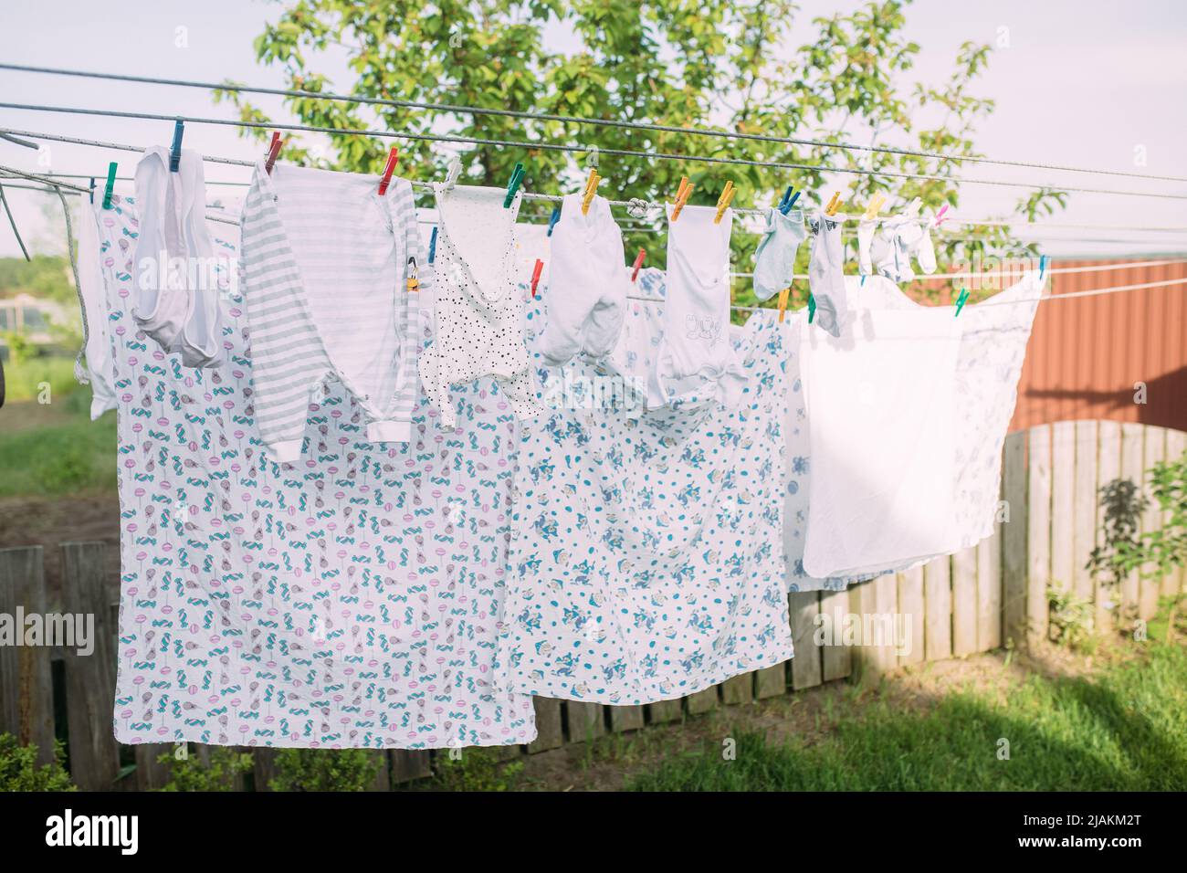 Clean washed newborn clothes are drying on a clothesline in the garden ...