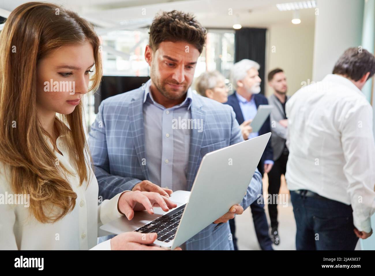 Two business people doing research together on a laptop PC in a ...