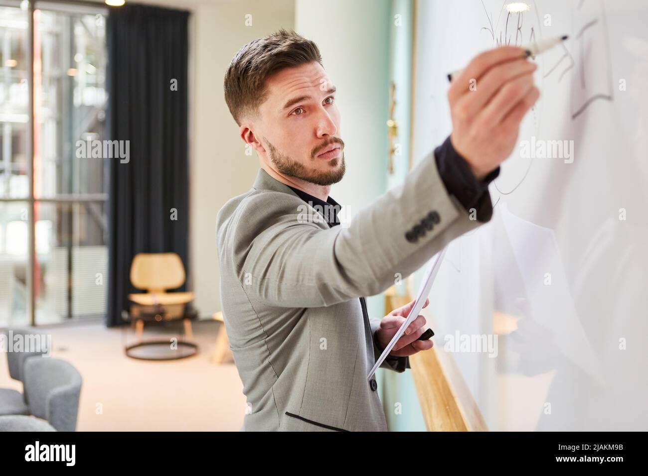 Young business man as a consultant or scientist at the whiteboard in a ...