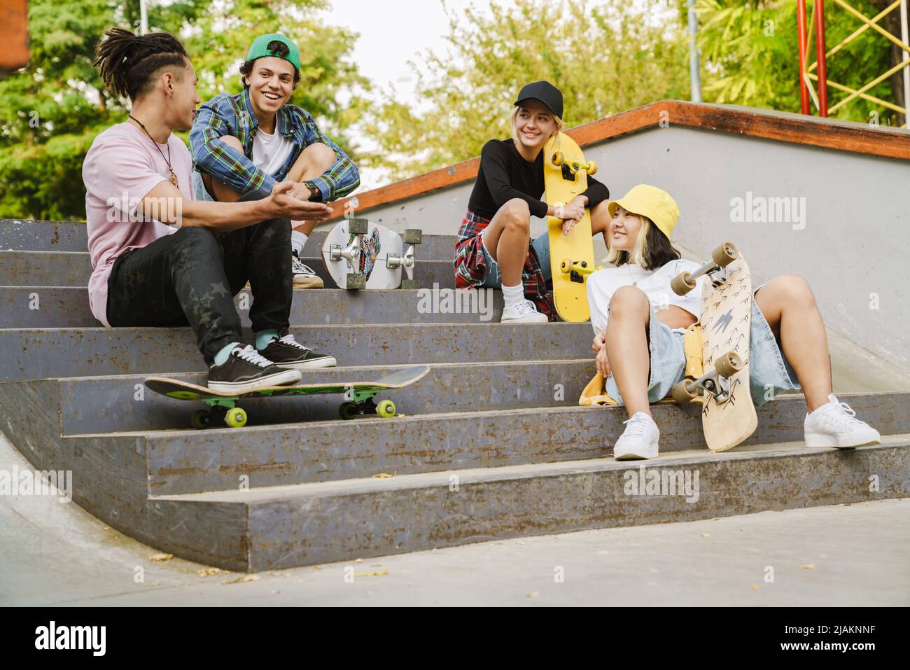Multiracial teenagers talking and laughing while spending time at skate ...