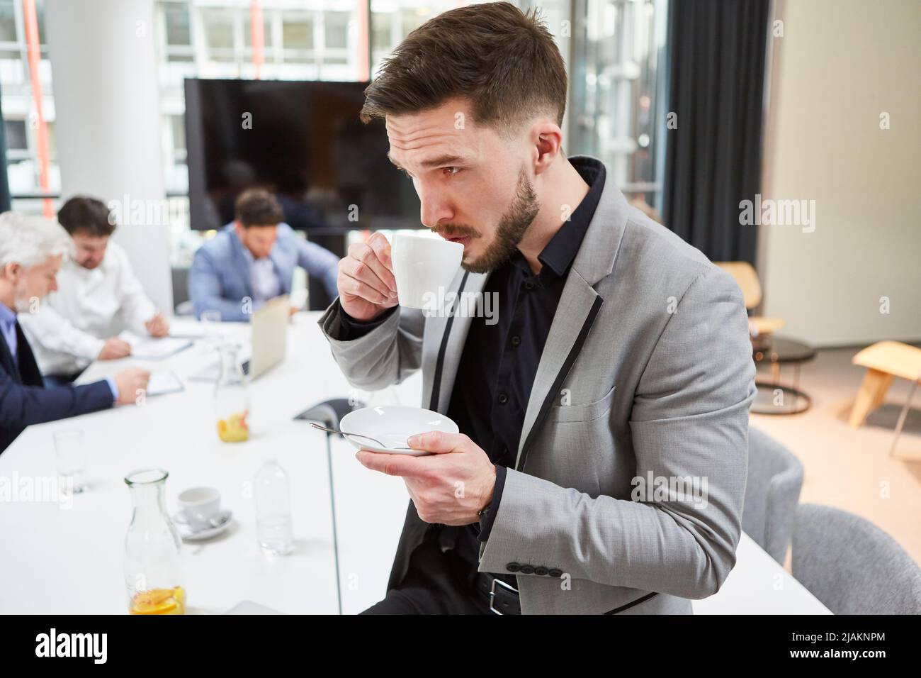 Young business man as a start-up founder drinks a cup of coffee in the ...