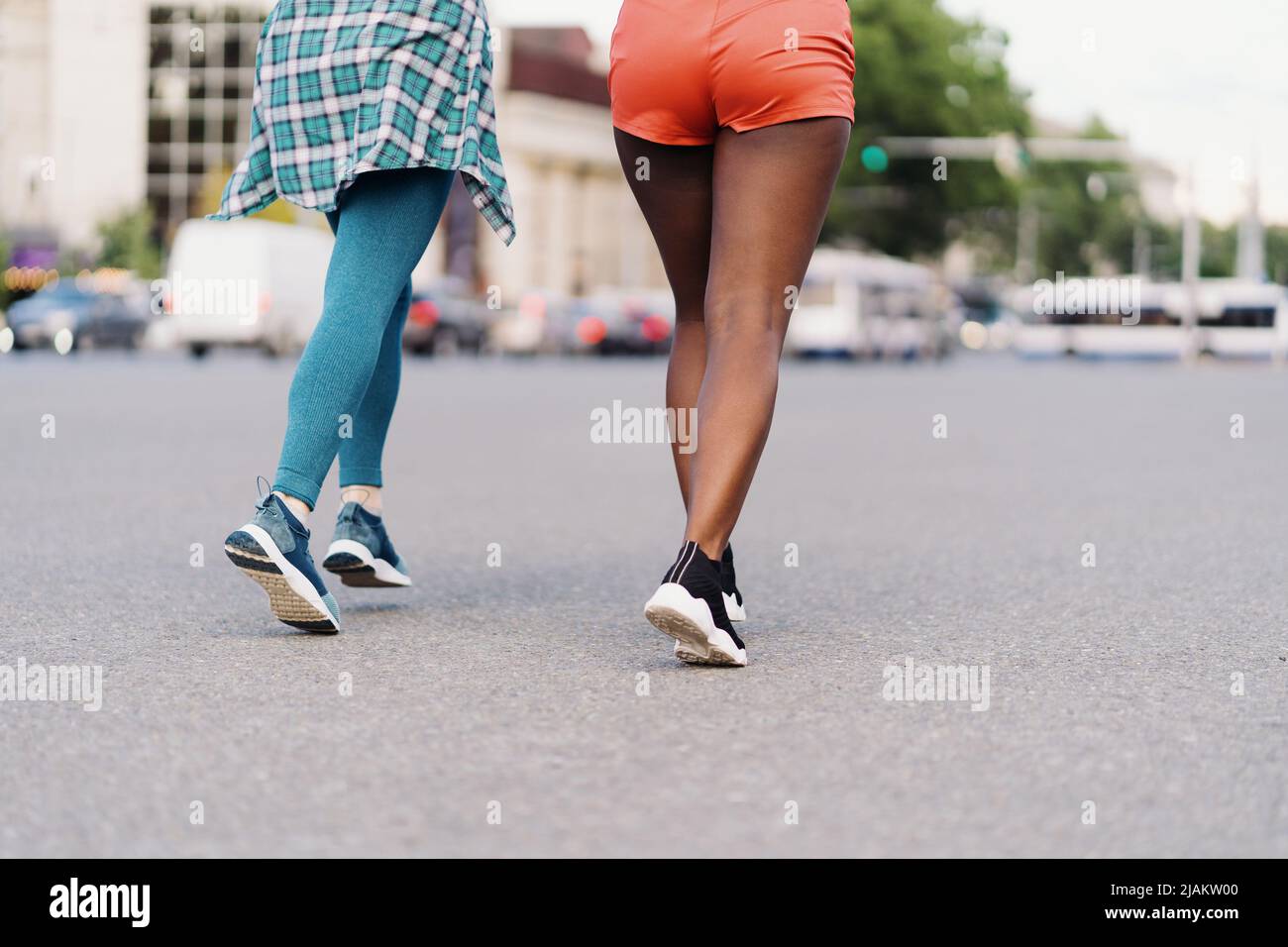 Back view of friends legs in sportswear running in the city ...