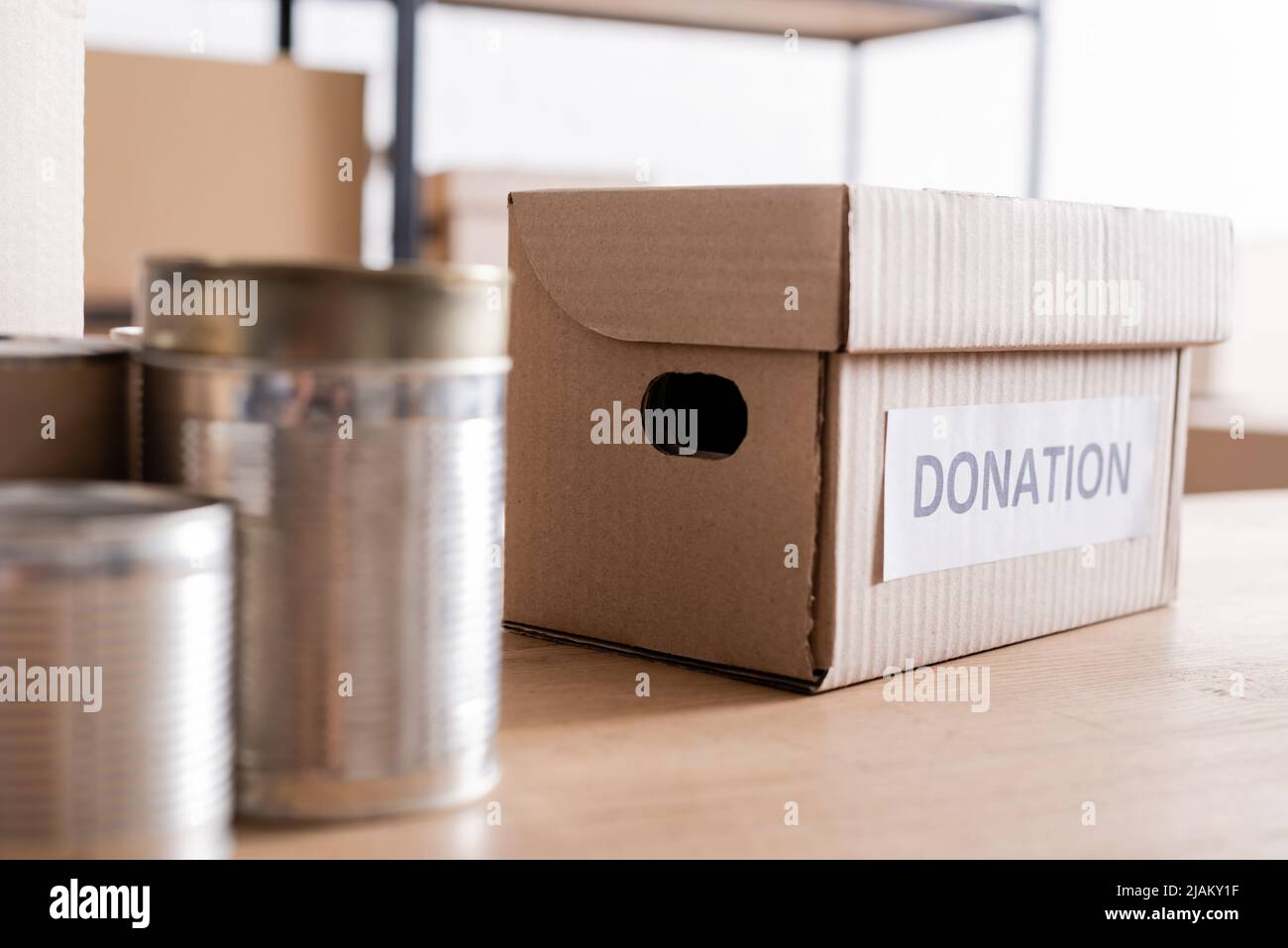 Box with donation lettering near blurred canned food on table Stock ...