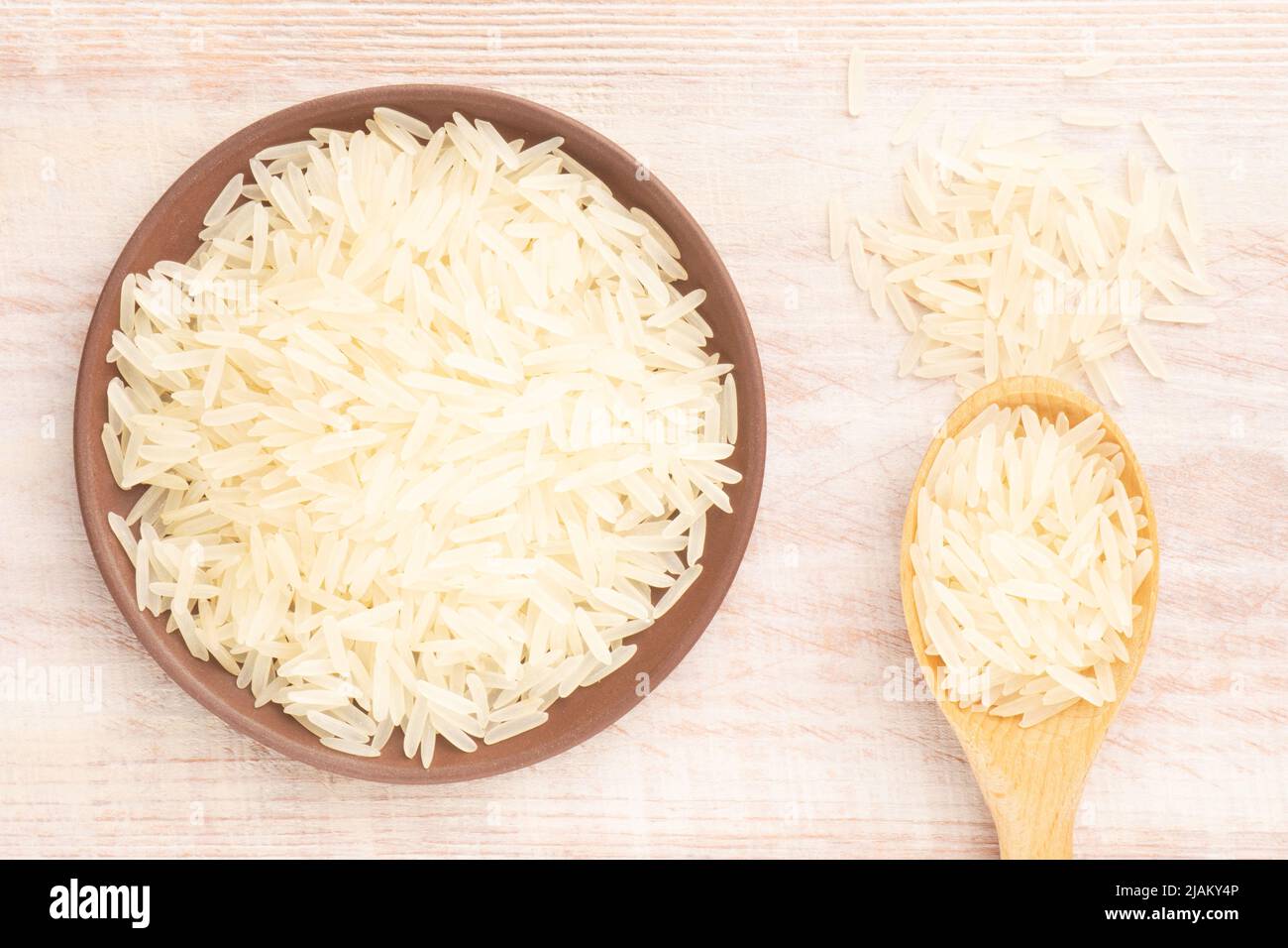 Long Basmati rice in clay plate spoon and bunch on brown wooden ...