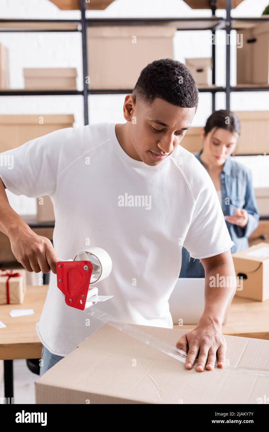 African american online web store owner packaging cardboard box with ...