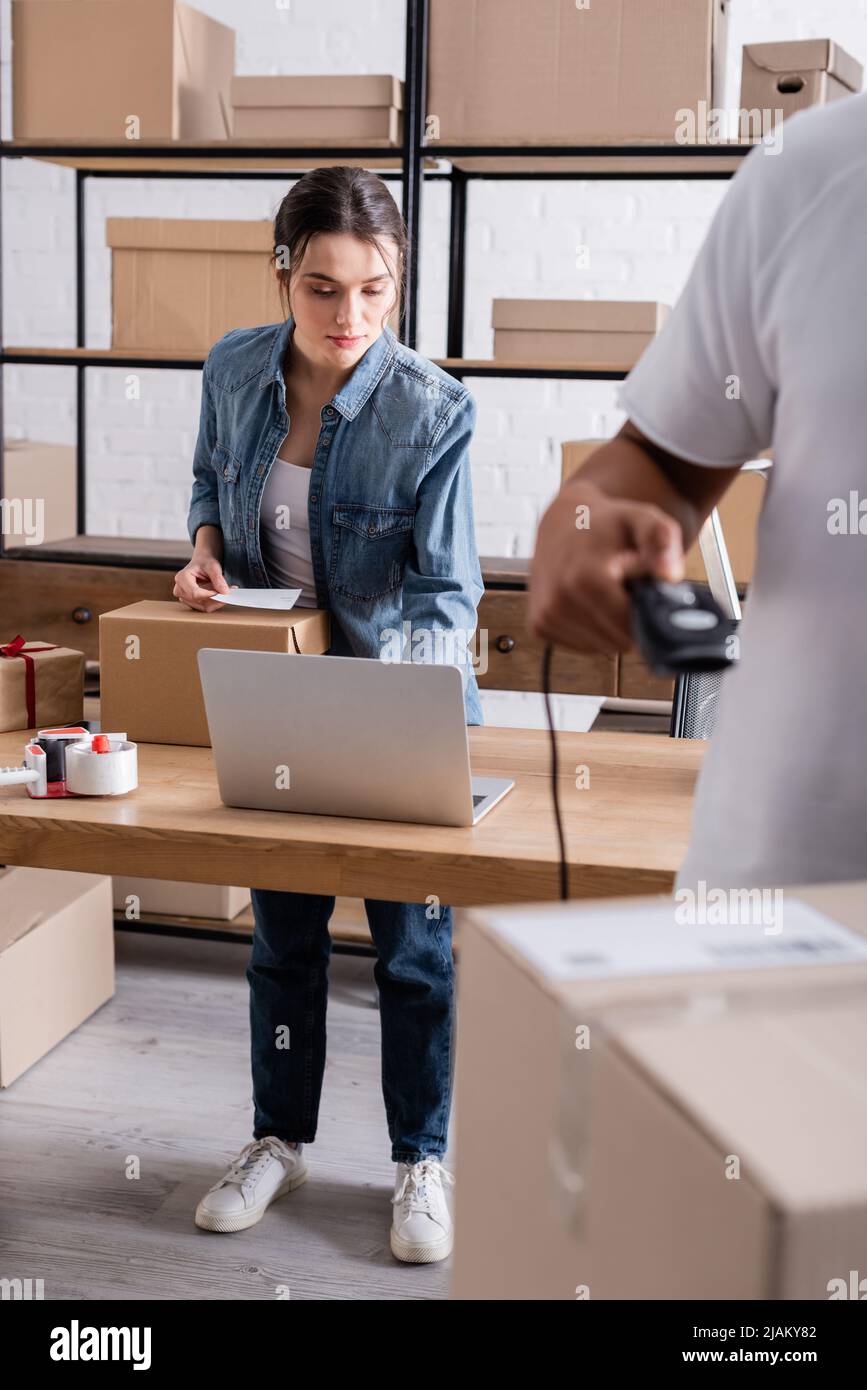Seller holding shipping label near packages and laptop in online web ...
