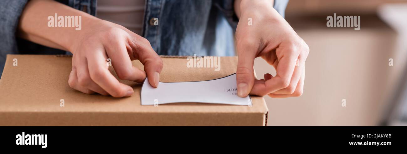 Cropped view of online web store owner fastening shipping label on ...