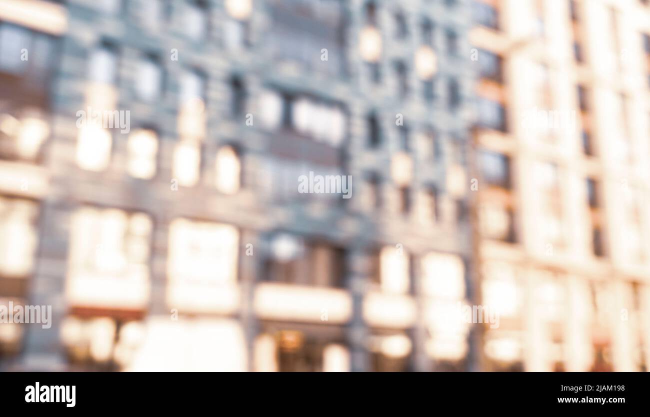 Abstract blurred building with illuminated facade exterior at the sunset. Blurry modern building ...