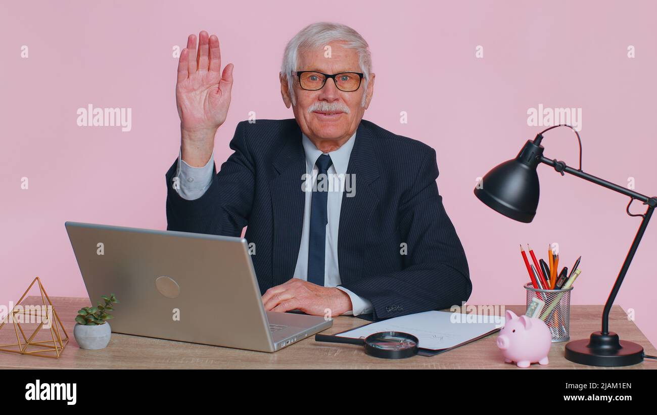 Hello. Senior business man employee wears glasses waves hand palm in hi ...