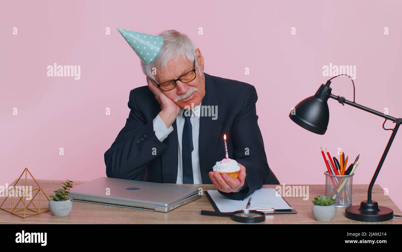 Sad upset lonely senior businessman in festive hat celebrating birthday ...