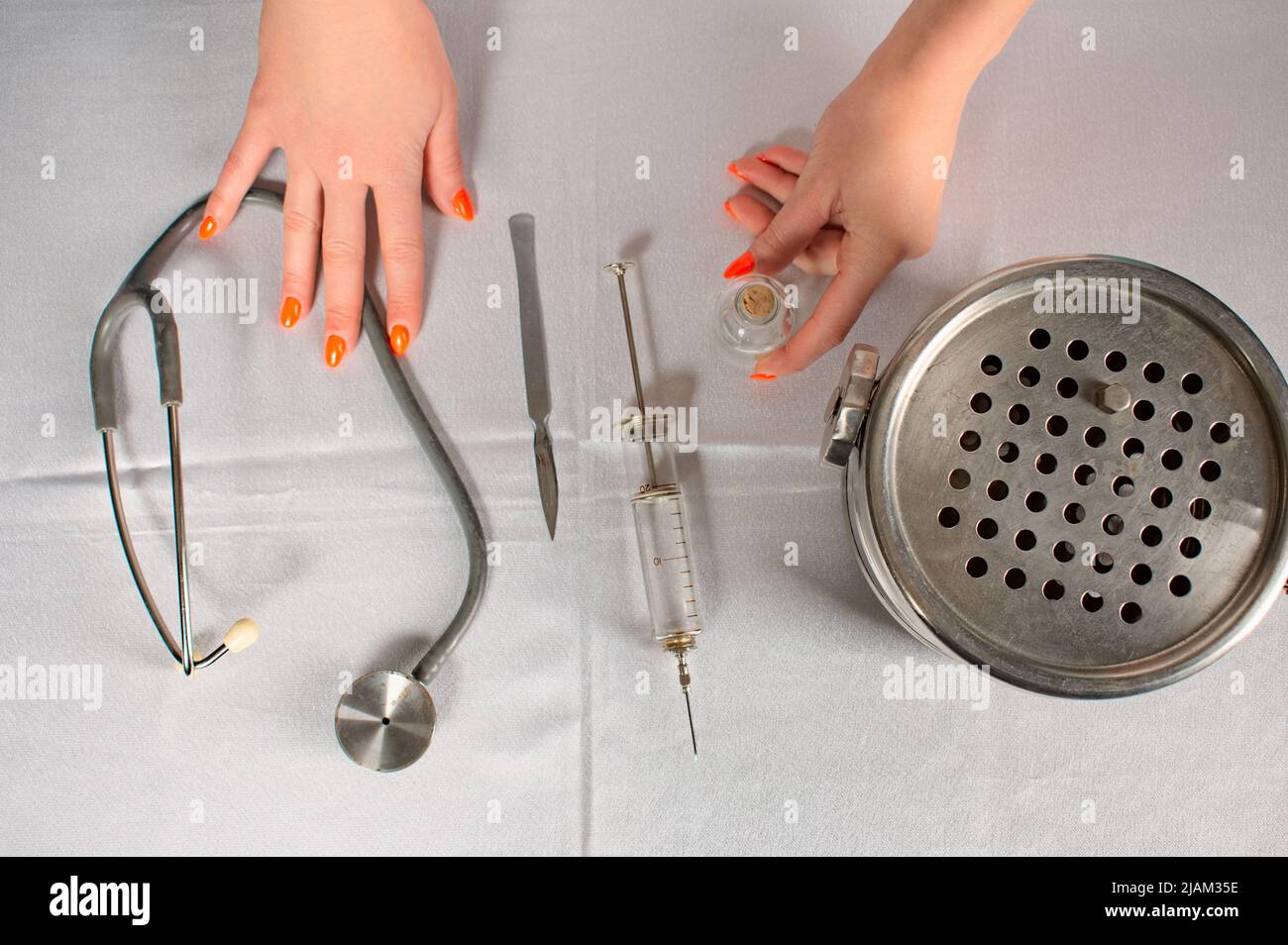 Doctors hands with medical equipment Statoscope, syringe, scalpel ...