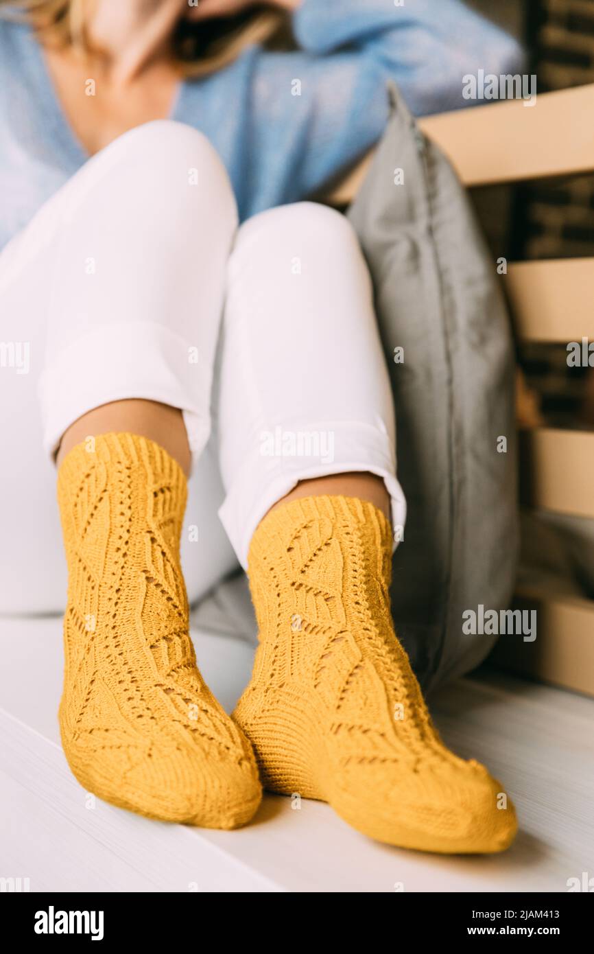 Close up of cozy woman in warm yellow knitted winter socks, white ...