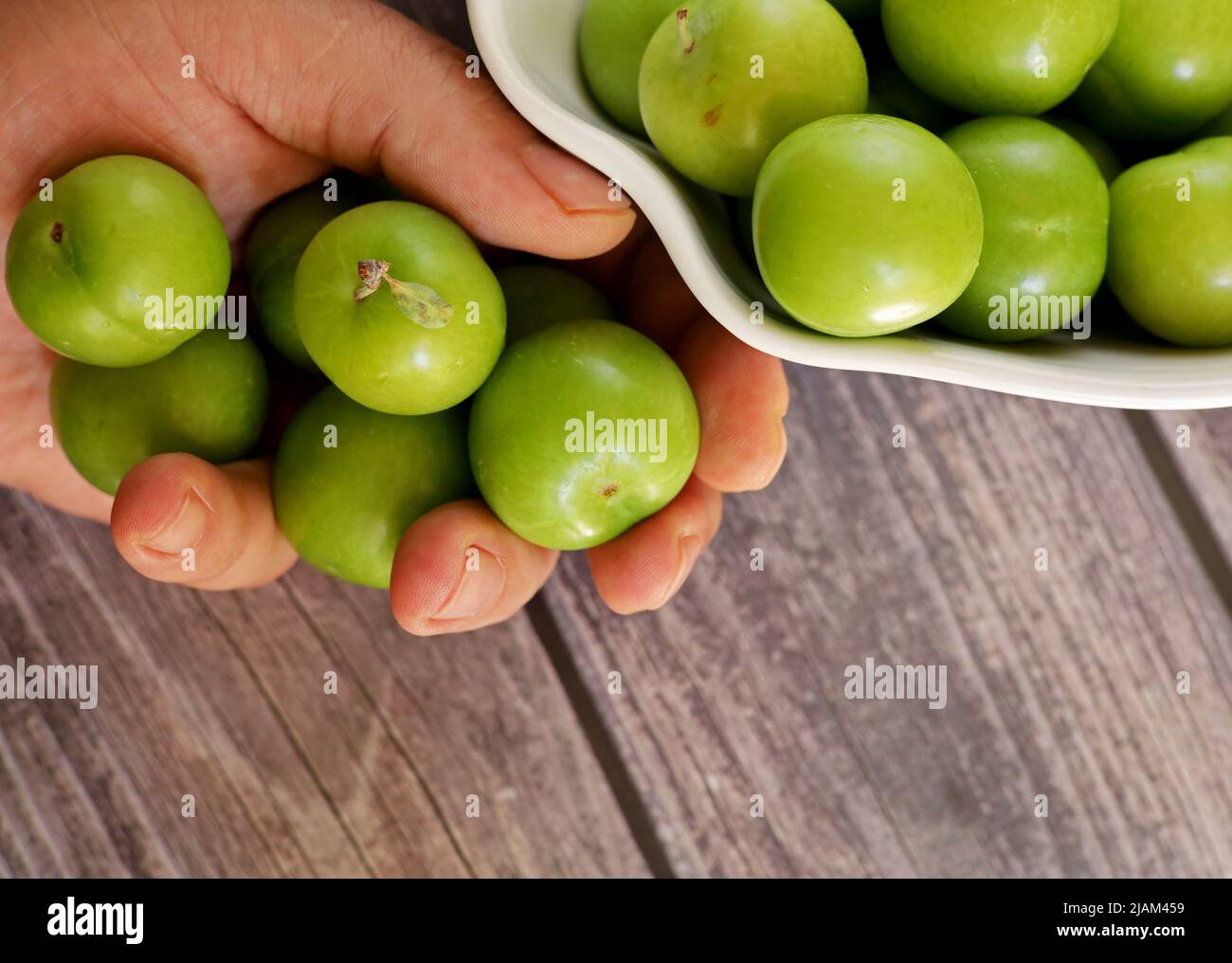 hand holding green plums on the table Stock Photo - Alamy