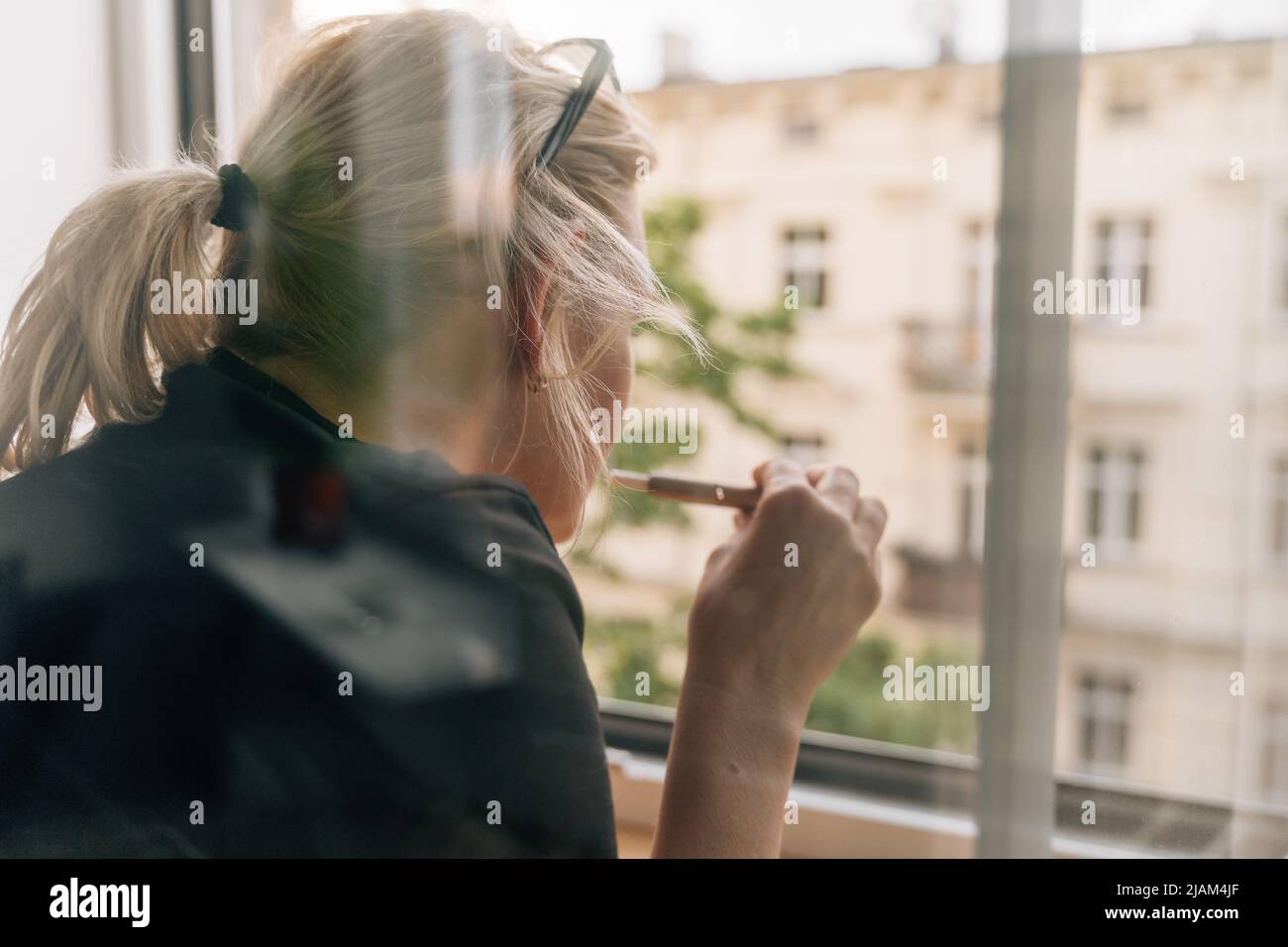 Mature Woman Smoking E Cigarette At Home Near The Window Caucasian 40 50 Years Old Female