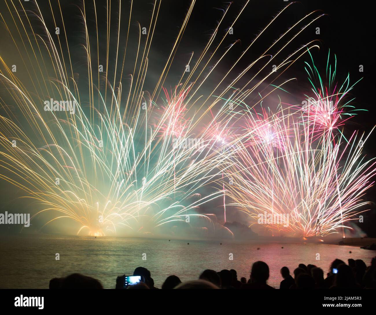 Bright firework show over water in dark sky Stock Photo - Alamy