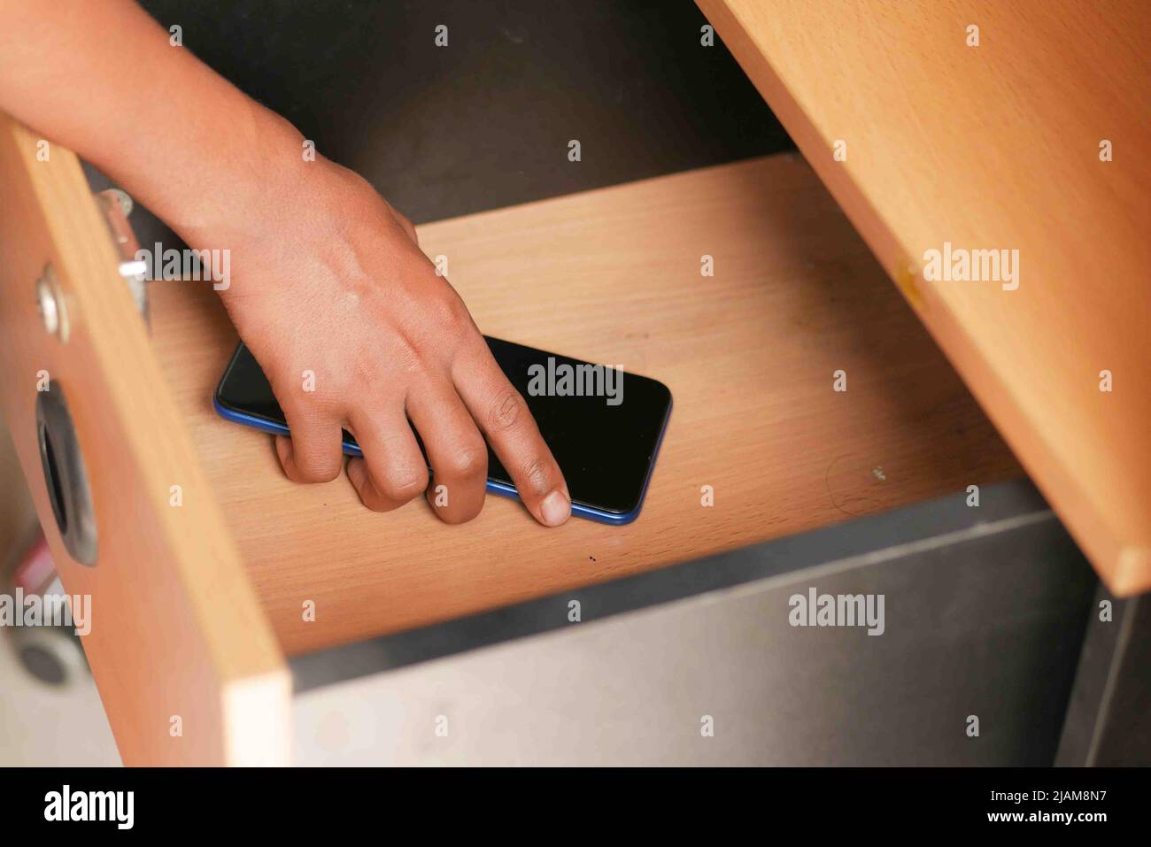 hand pick a smart phone from a drawer Stock Photo - Alamy