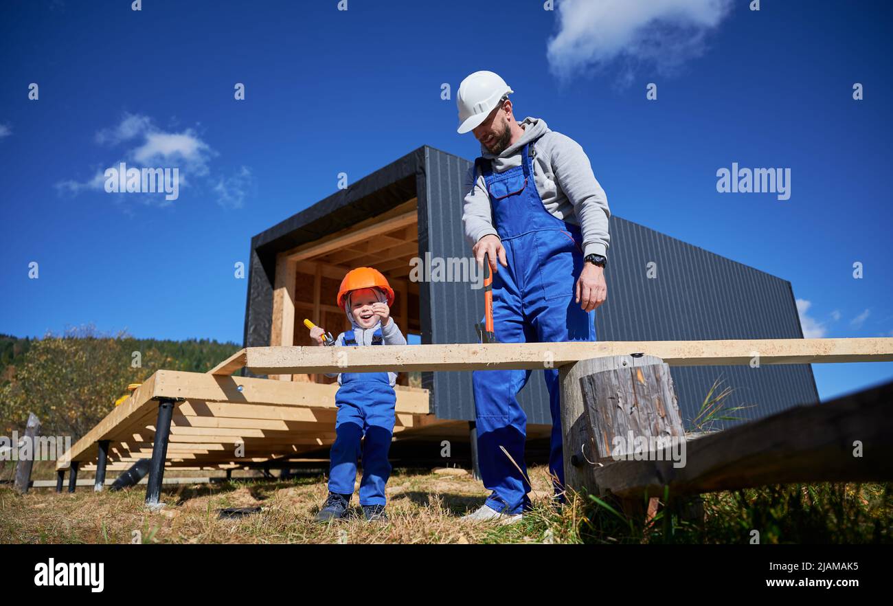 Father with toddler son building wooden frame house. Male builders ...
