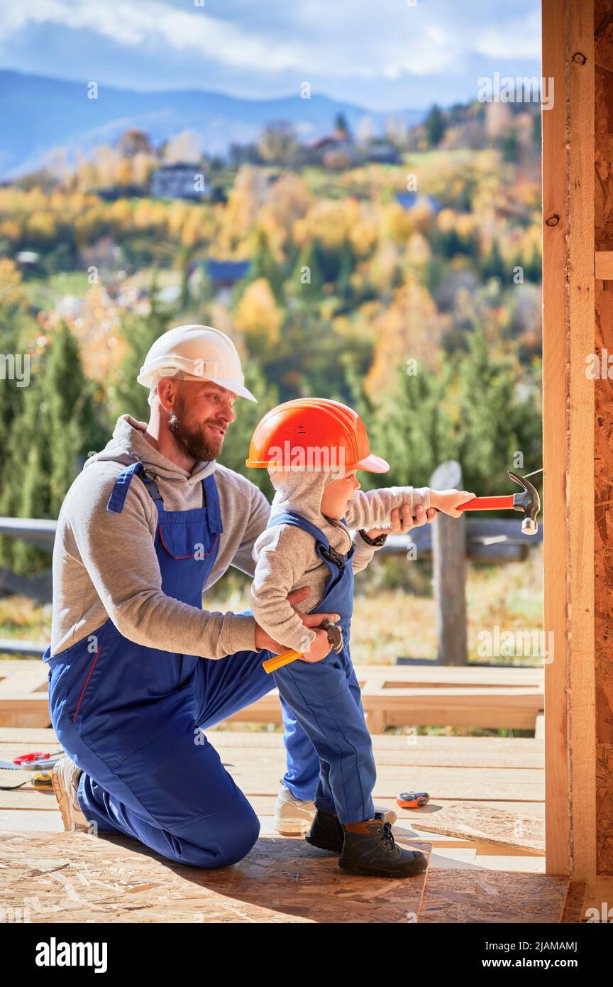 Father with toddler son building wooden frame house. Boy helping his ...