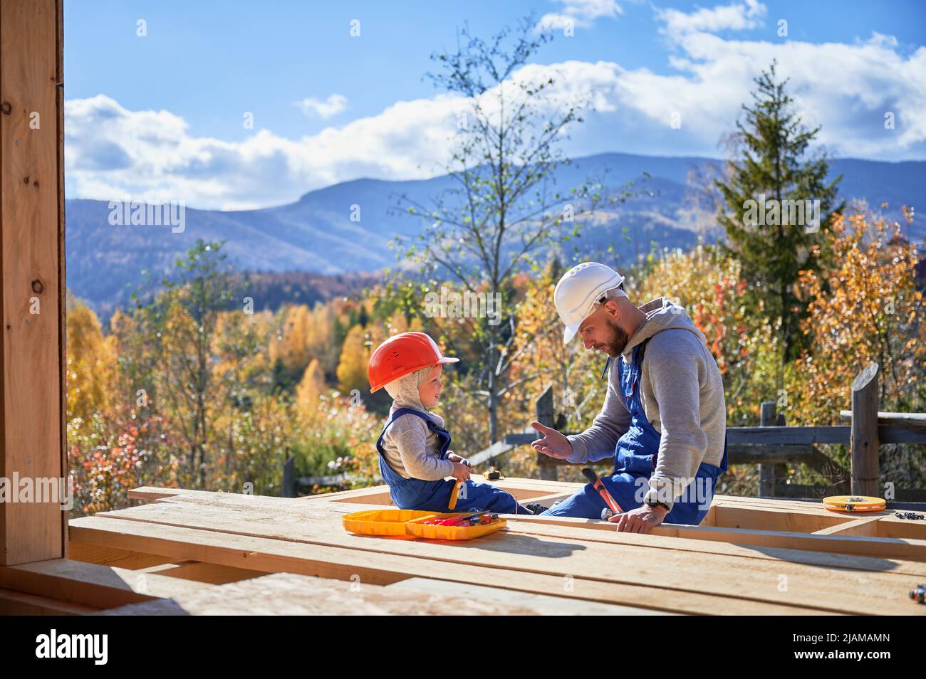 Father with toddler son building wooden frame house. Male builders ...