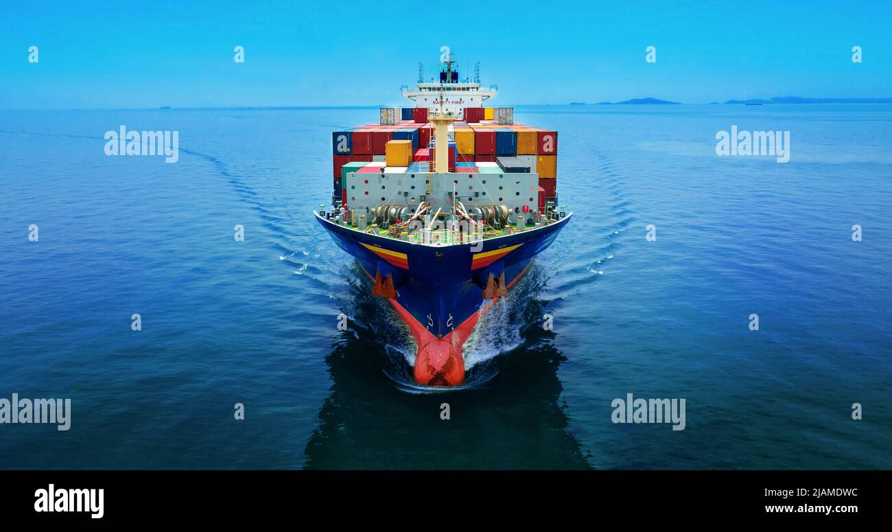 Aerial in front view of cargo ship carrying container and running for ...