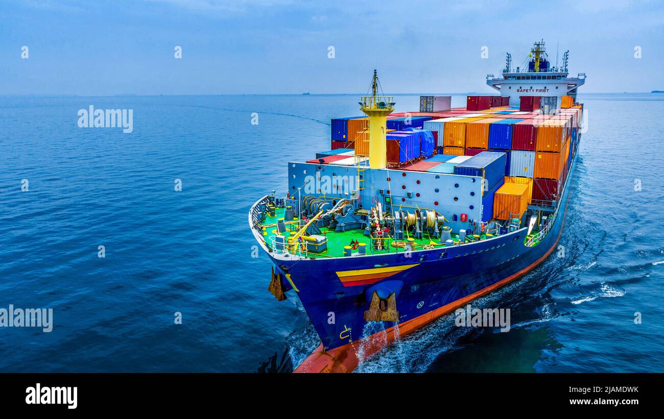 Aerial in front view of cargo ship carrying container and running for ...
