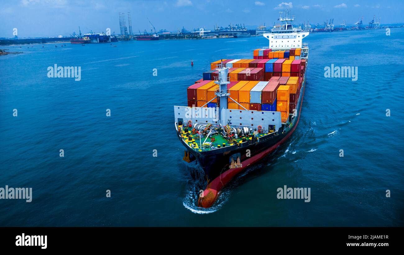 Aerial in front view of cargo ship carrying container and running for ...