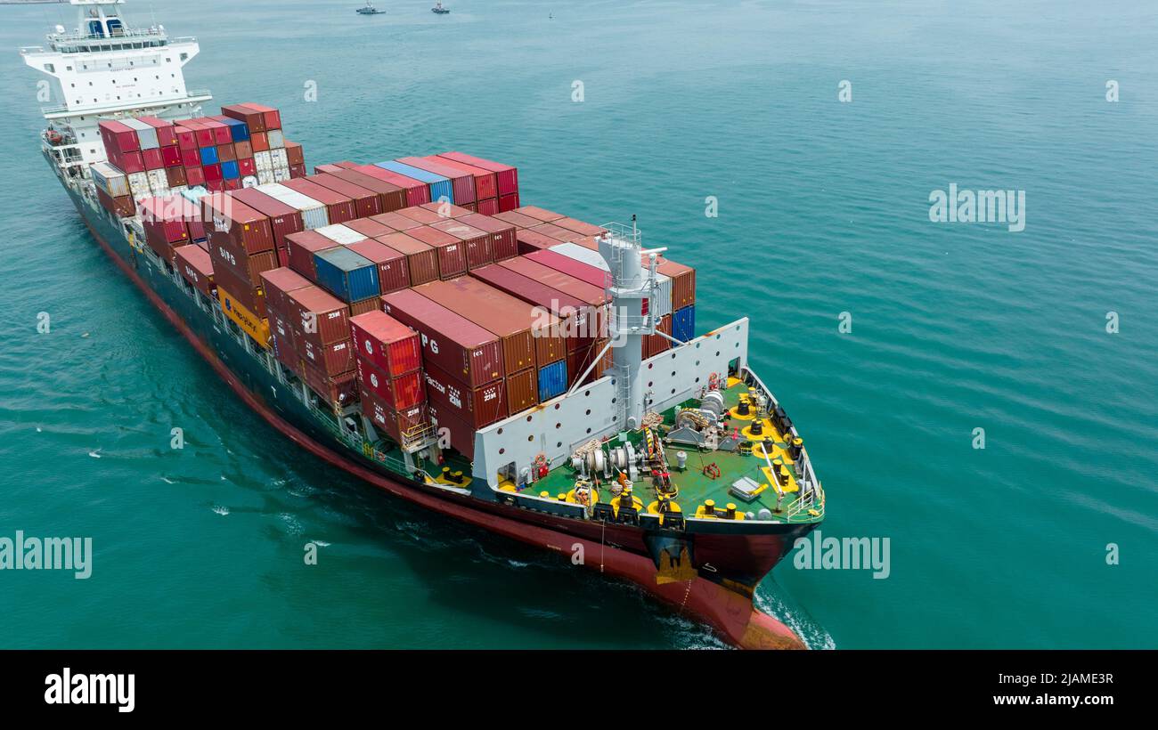 Aerial side view of cargo ship carrying container and running for ...