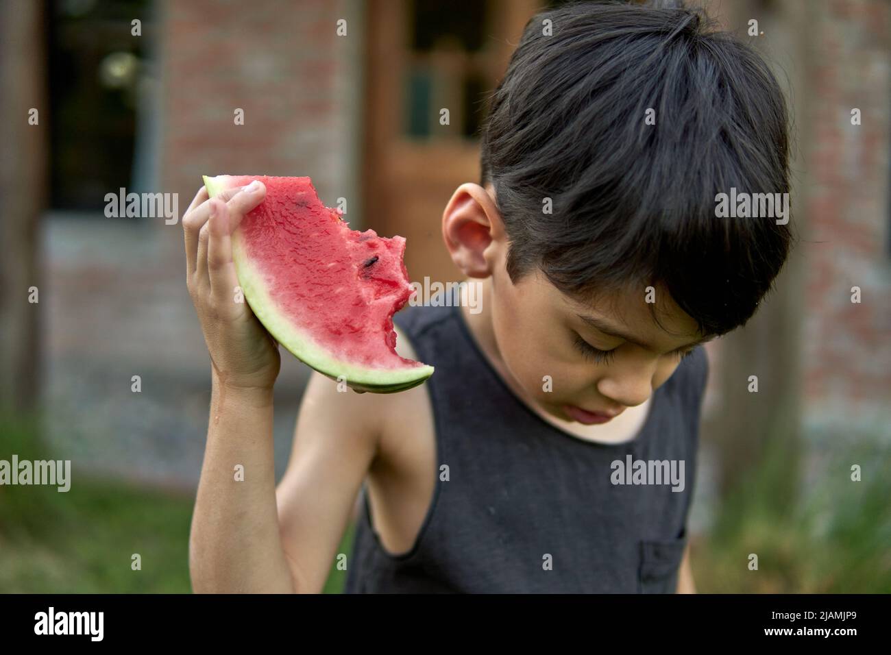 argentine child holding a slice of watermelon with one hand and looking ...