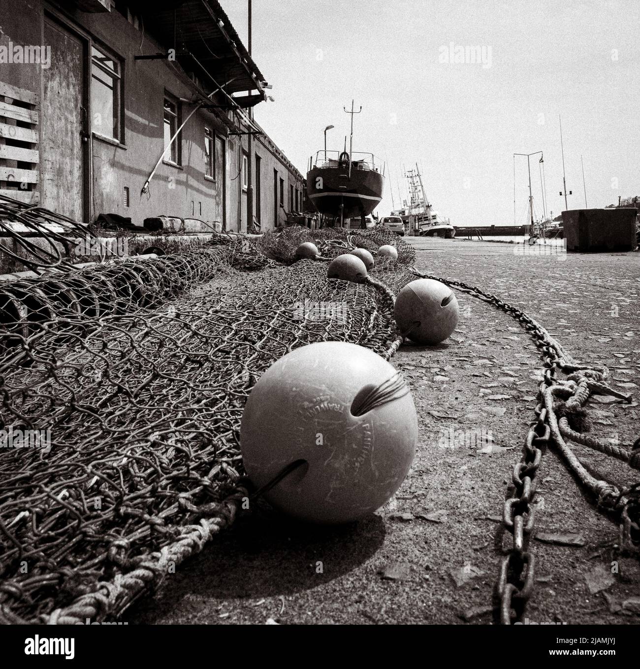 Fishing nets, chains and buoys spread along the Newlyn port quayside ...