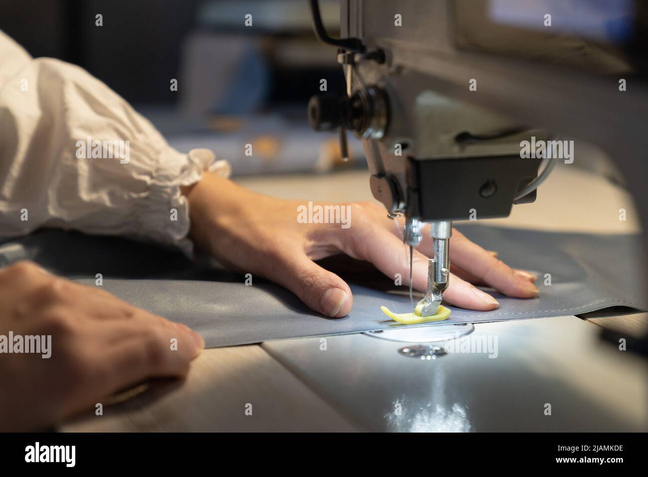 Closeup of female tailor work on sewing machine stitch fabric patterns ...