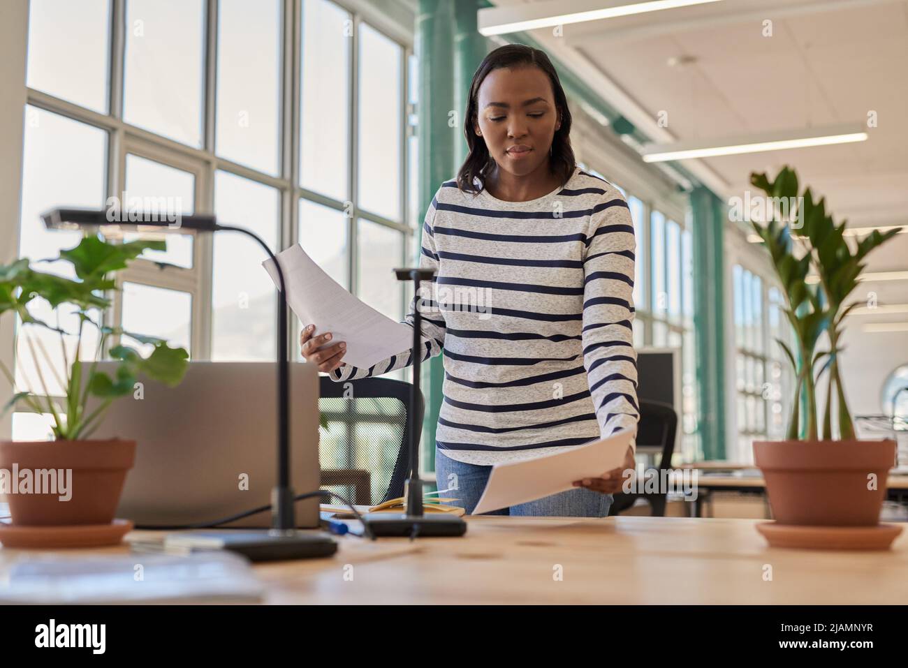 Young African businesswoman going over paperwork at her office desk ...