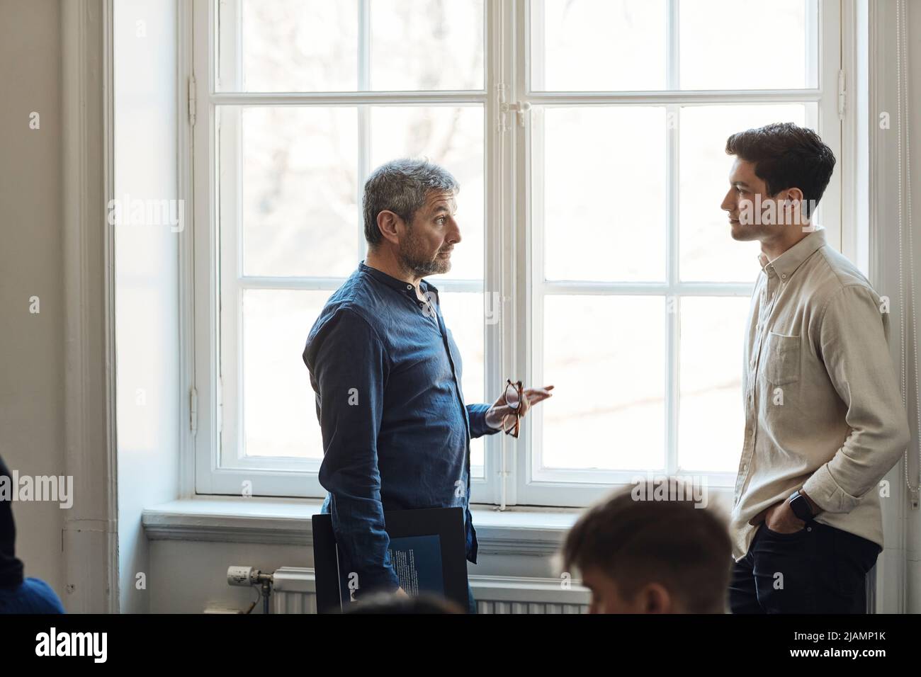 Male professor talking with student near window in university Stock ...