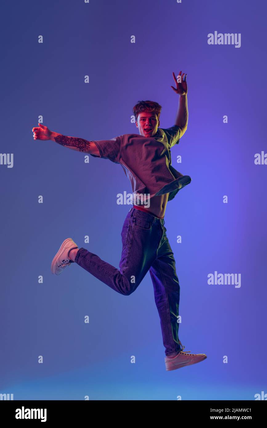 Young red-headed man, student jumping isolated over blue studio ...