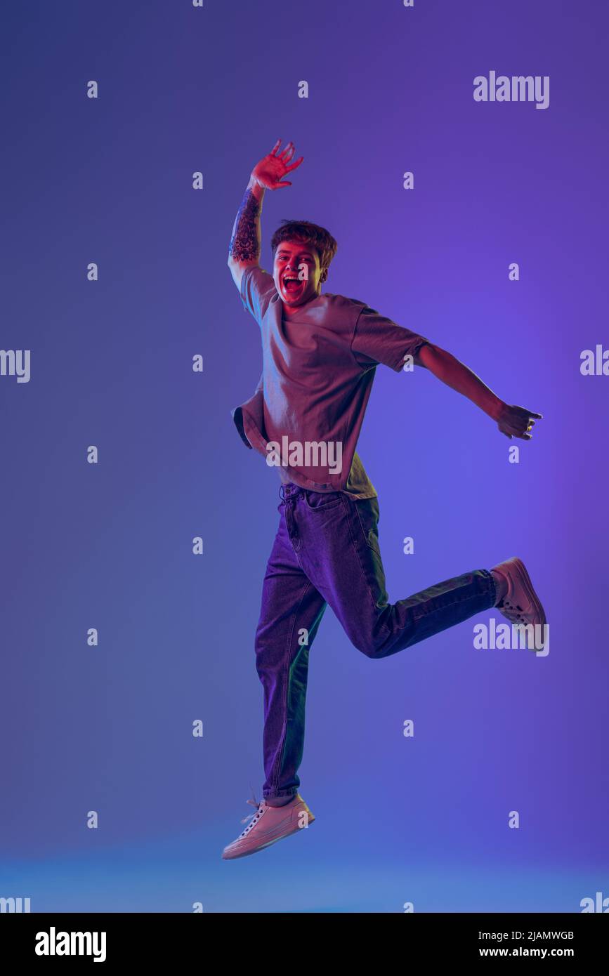 Young red-headed man, student jumping isolated over blue studio ...