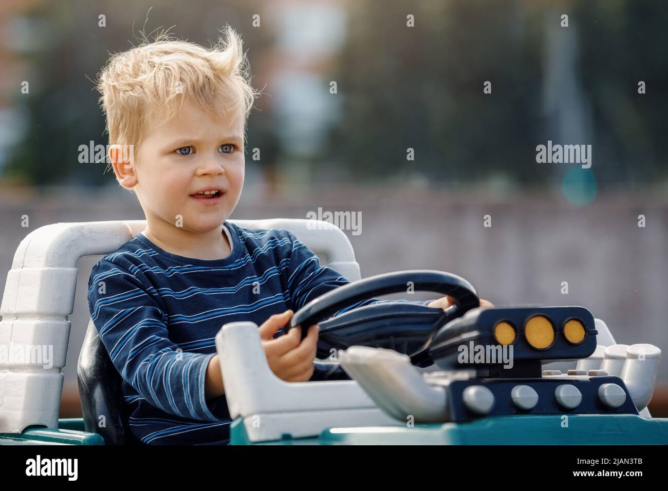 Little boy driving big toy car with steering wheel and having fun ...