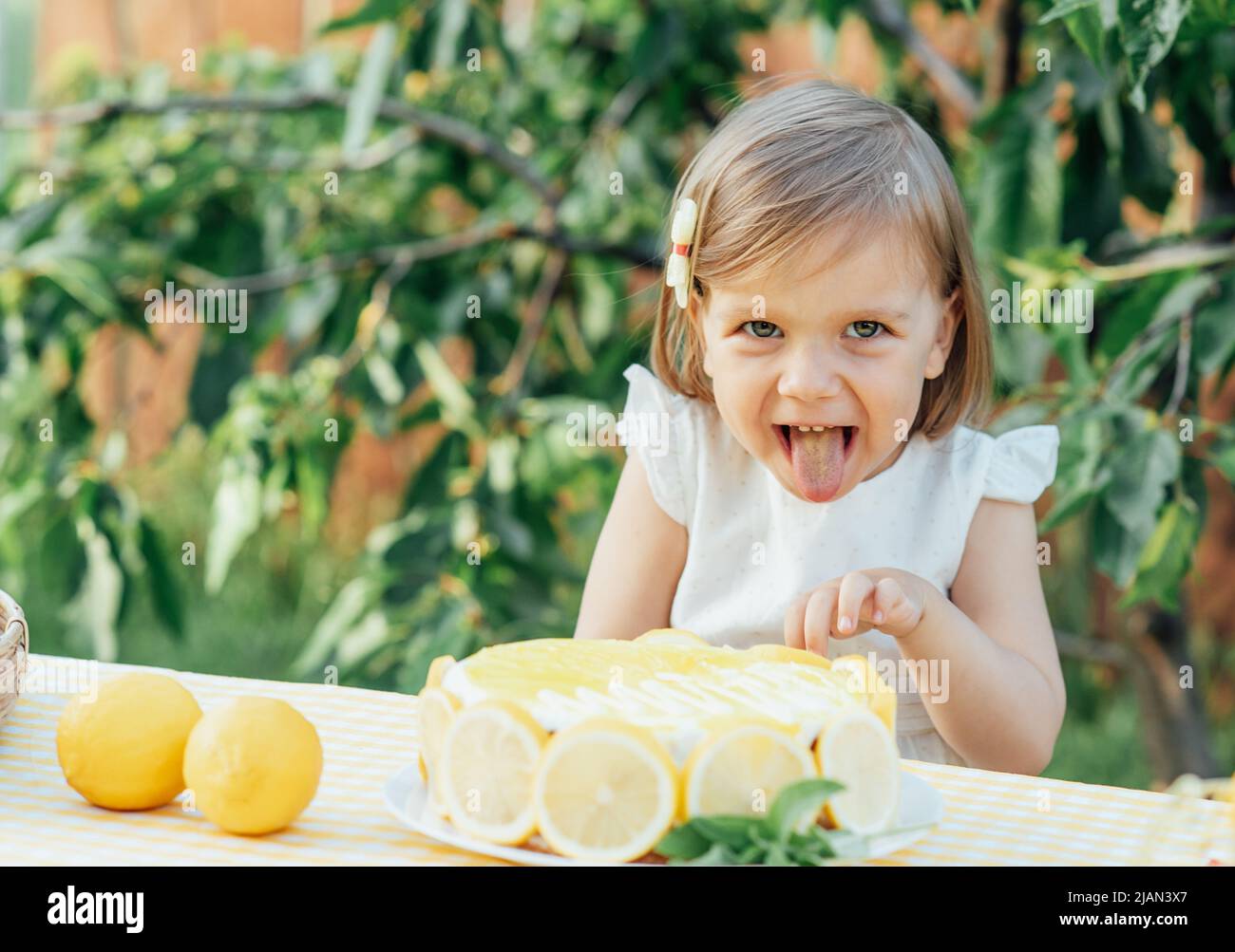 girl eating lemon Birthday cake. Lemonade birthday party at summer park ...