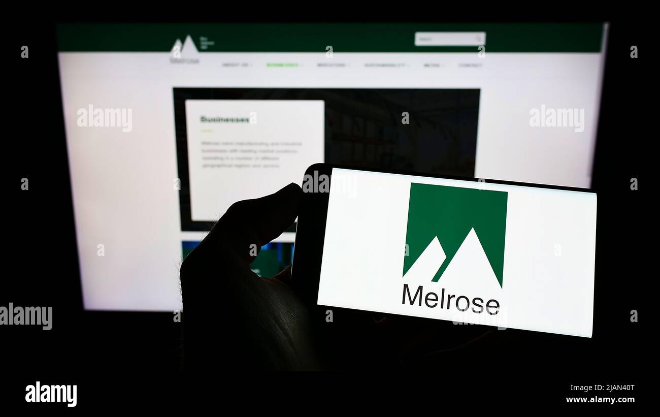 Person holding cellphone with logo of British company Melrose ...