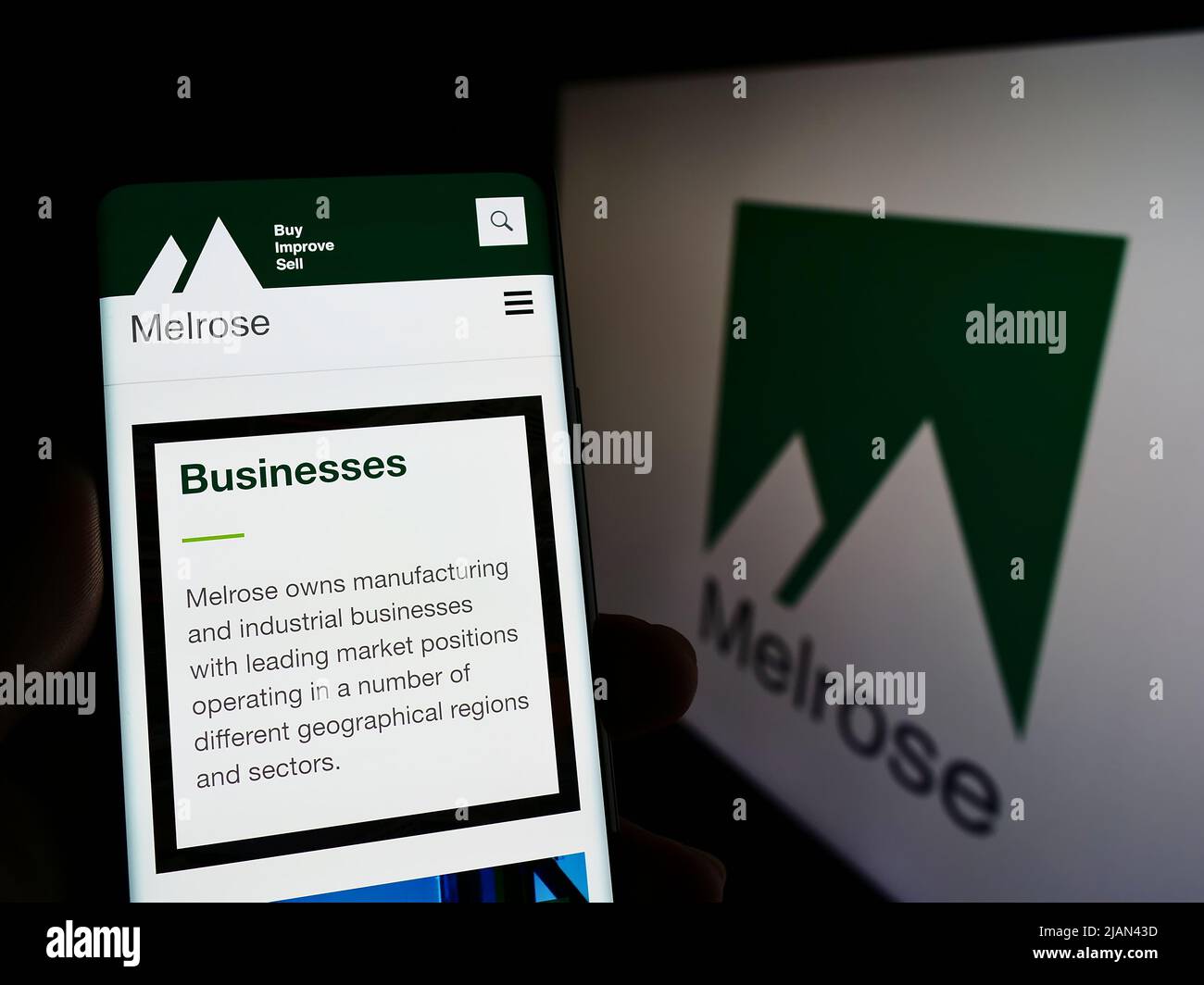 Person holding cellphone with website of British company Melrose ...